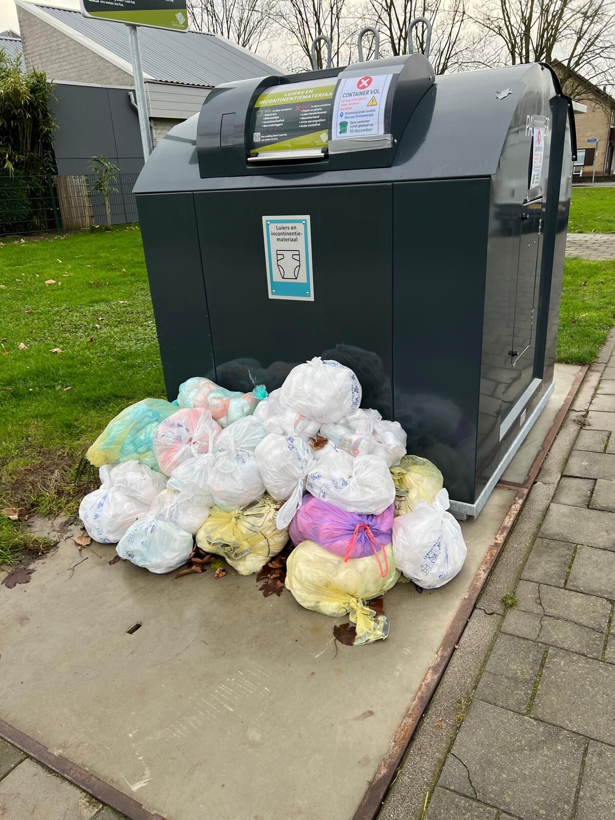 Zakken met volle poepluiers stapelen zich op voor de luiercontainer ...